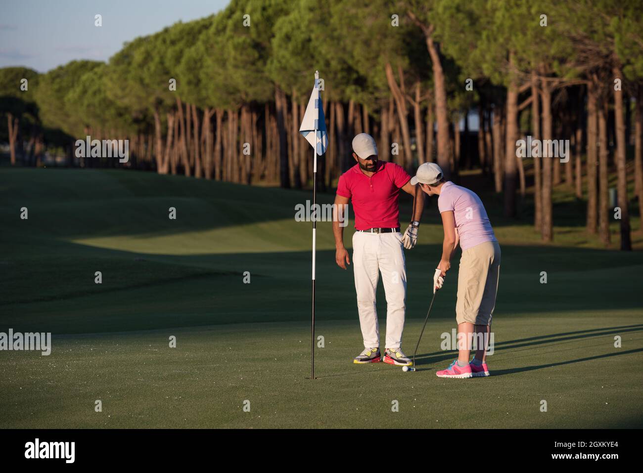 male golf instructor teaching female golf player, personal trainer ...
