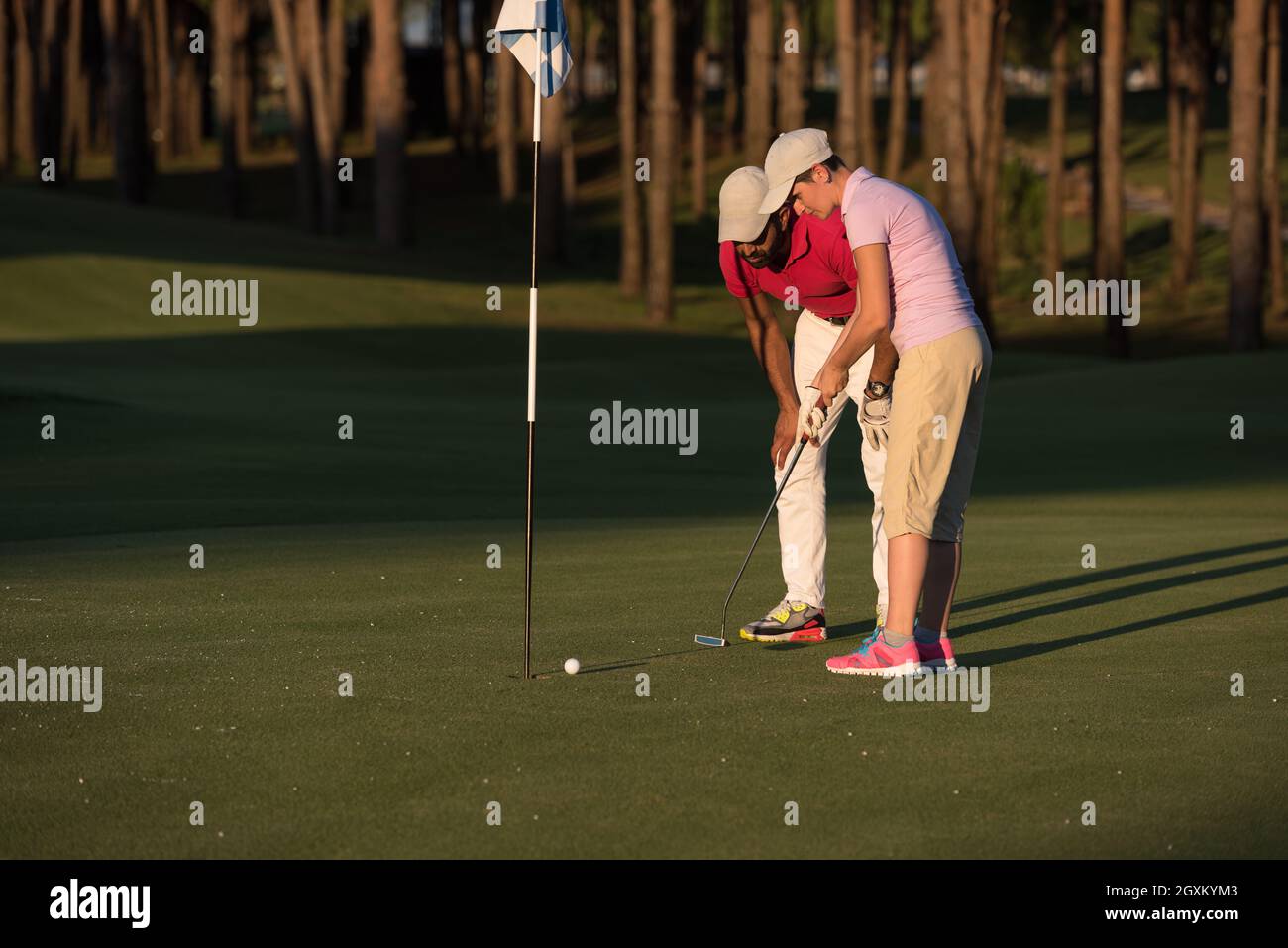male golf instructor teaching female golf player, personal trainer ...