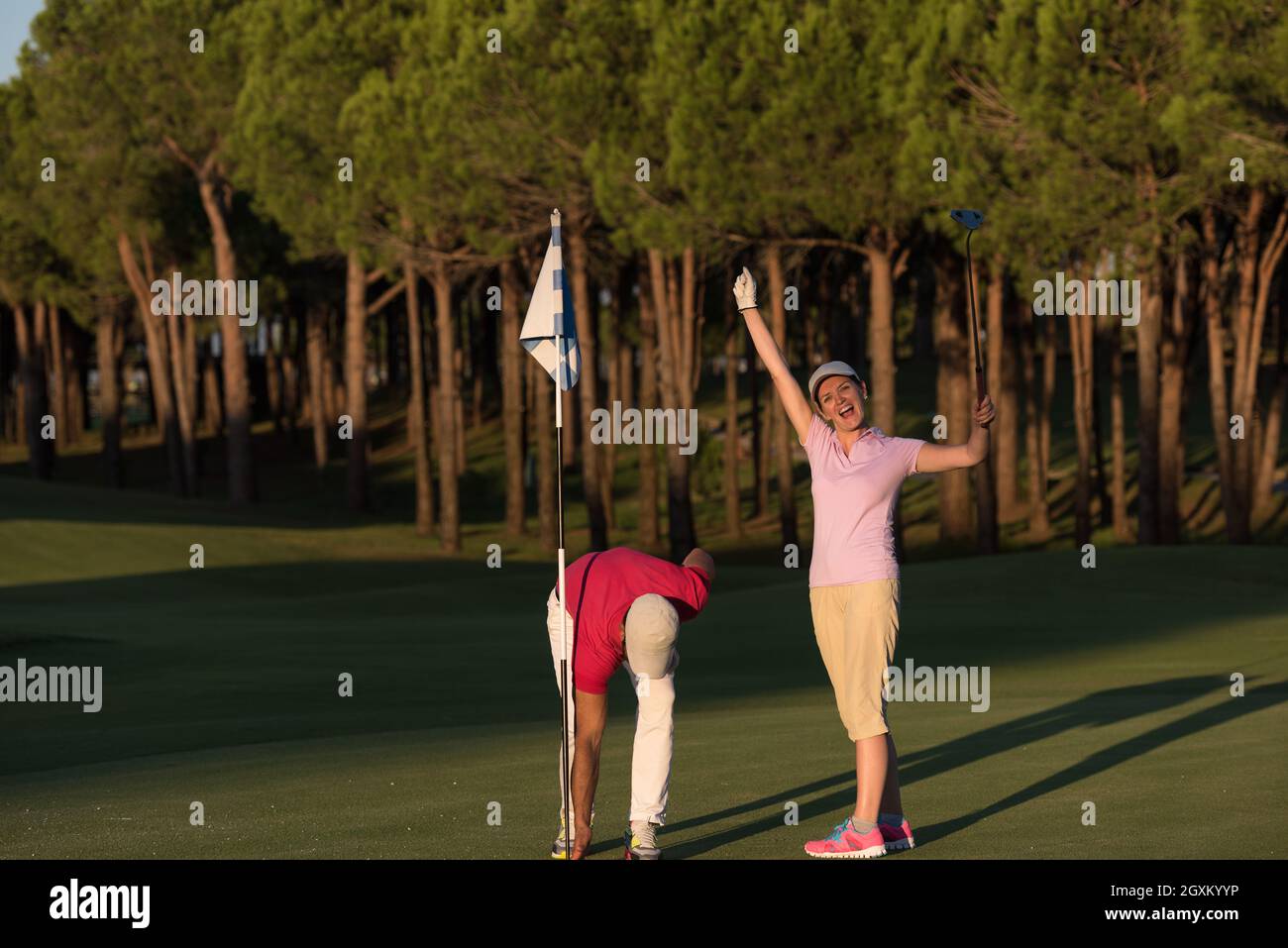 male golf instructor teaching female golf player, personal trainer ...