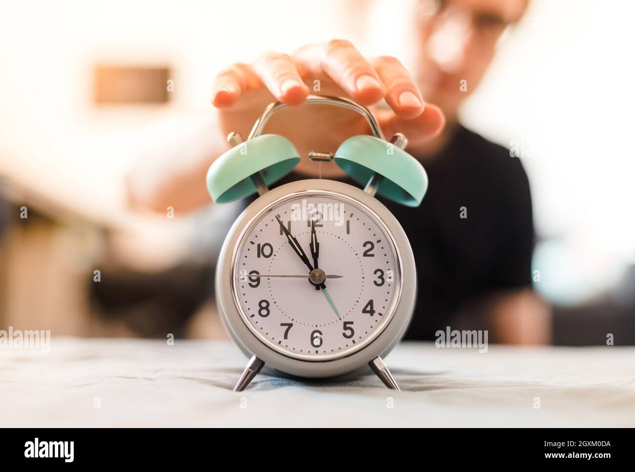 Man is pushing an alarm clock, sunshine in the morning, blurry ...