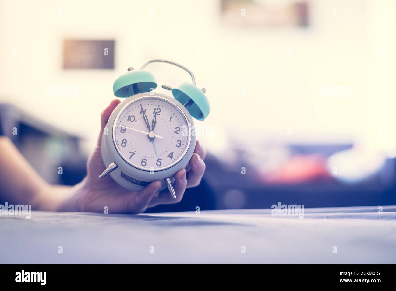 Man is holding an alarm clock, sunshine in the morning, blurry ...