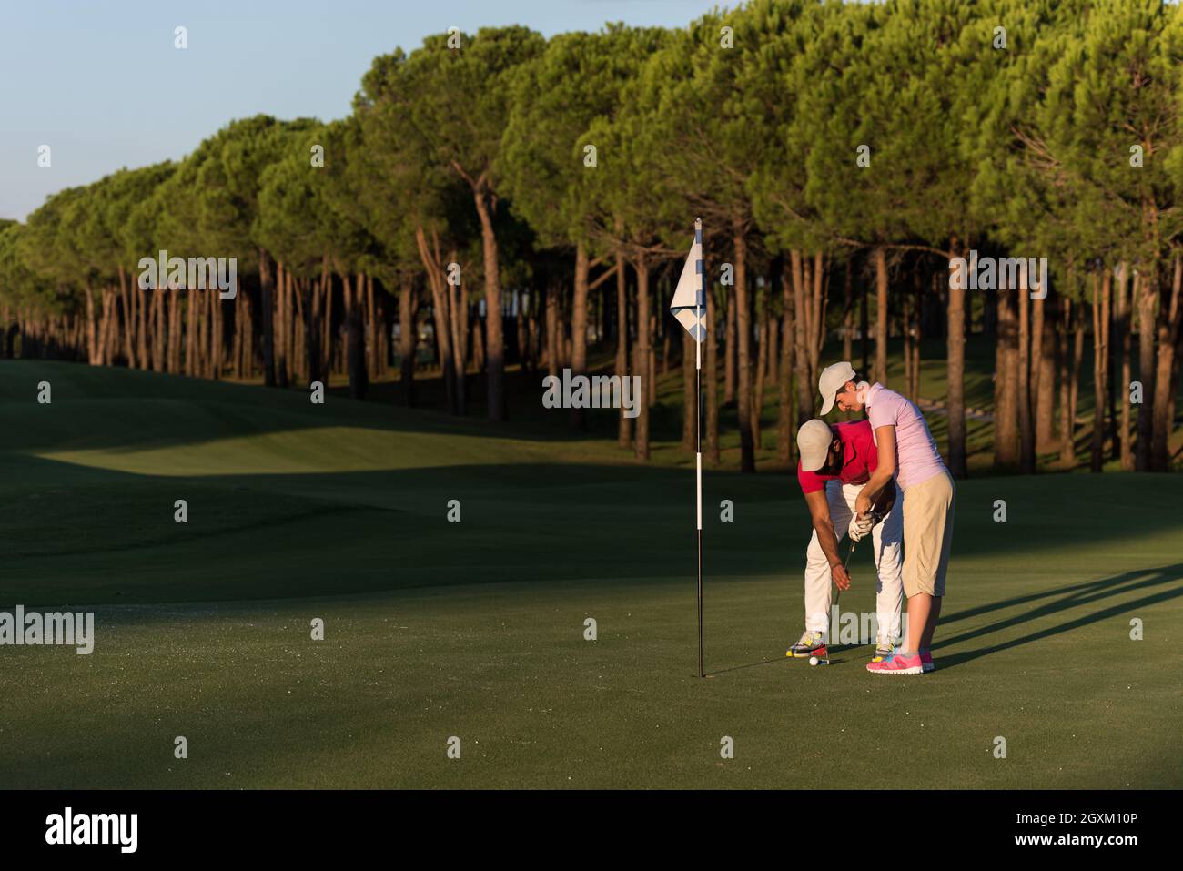 male golf instructor teaching female golf player, personal trainer ...