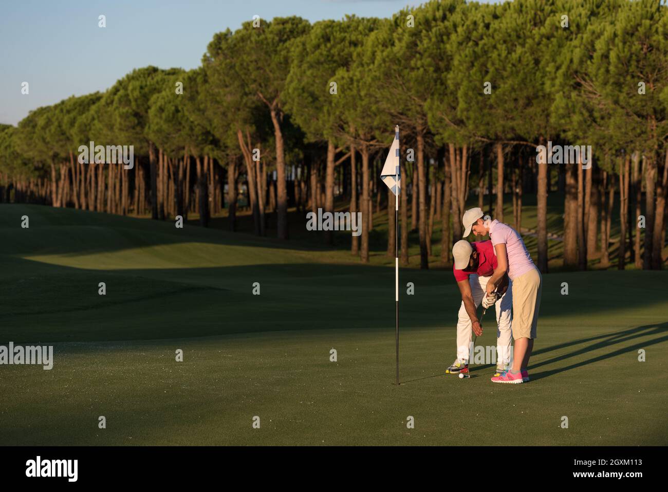 male golf instructor teaching female golf player, personal trainer ...