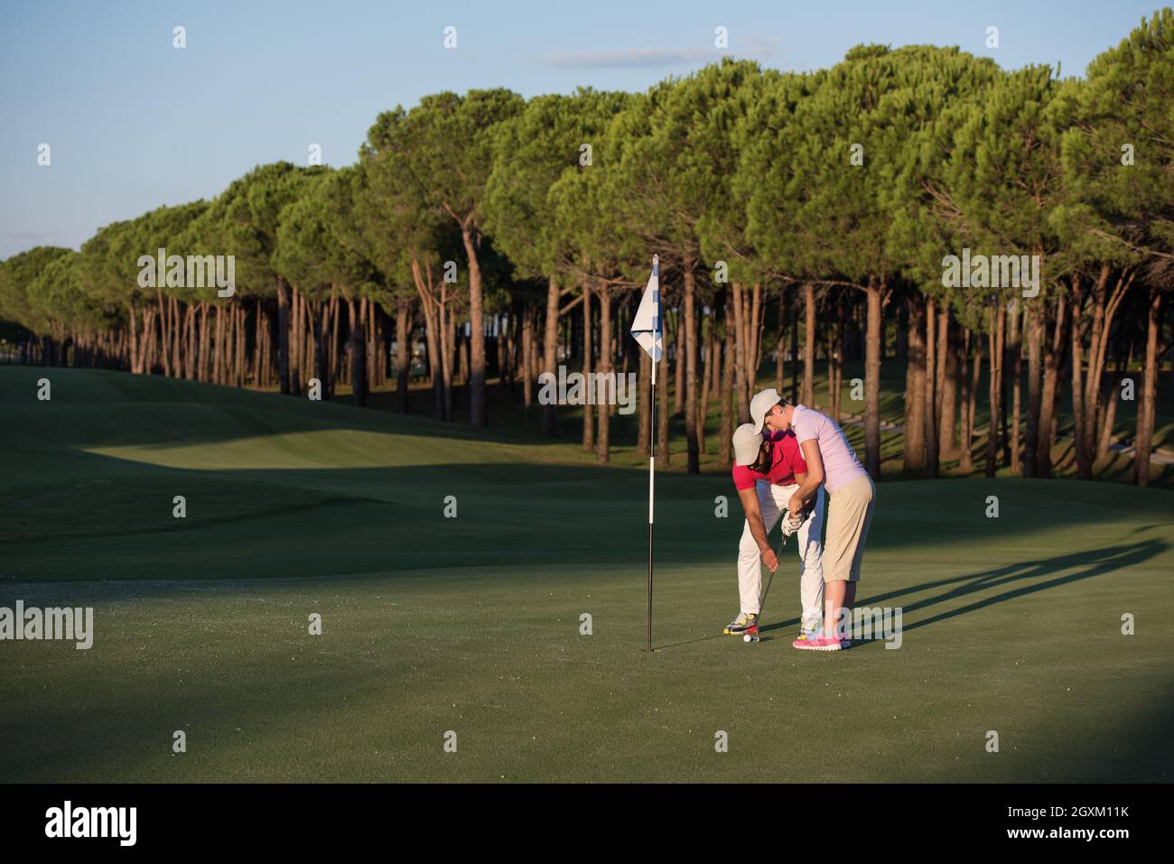 male golf instructor teaching female golf player, personal trainer ...