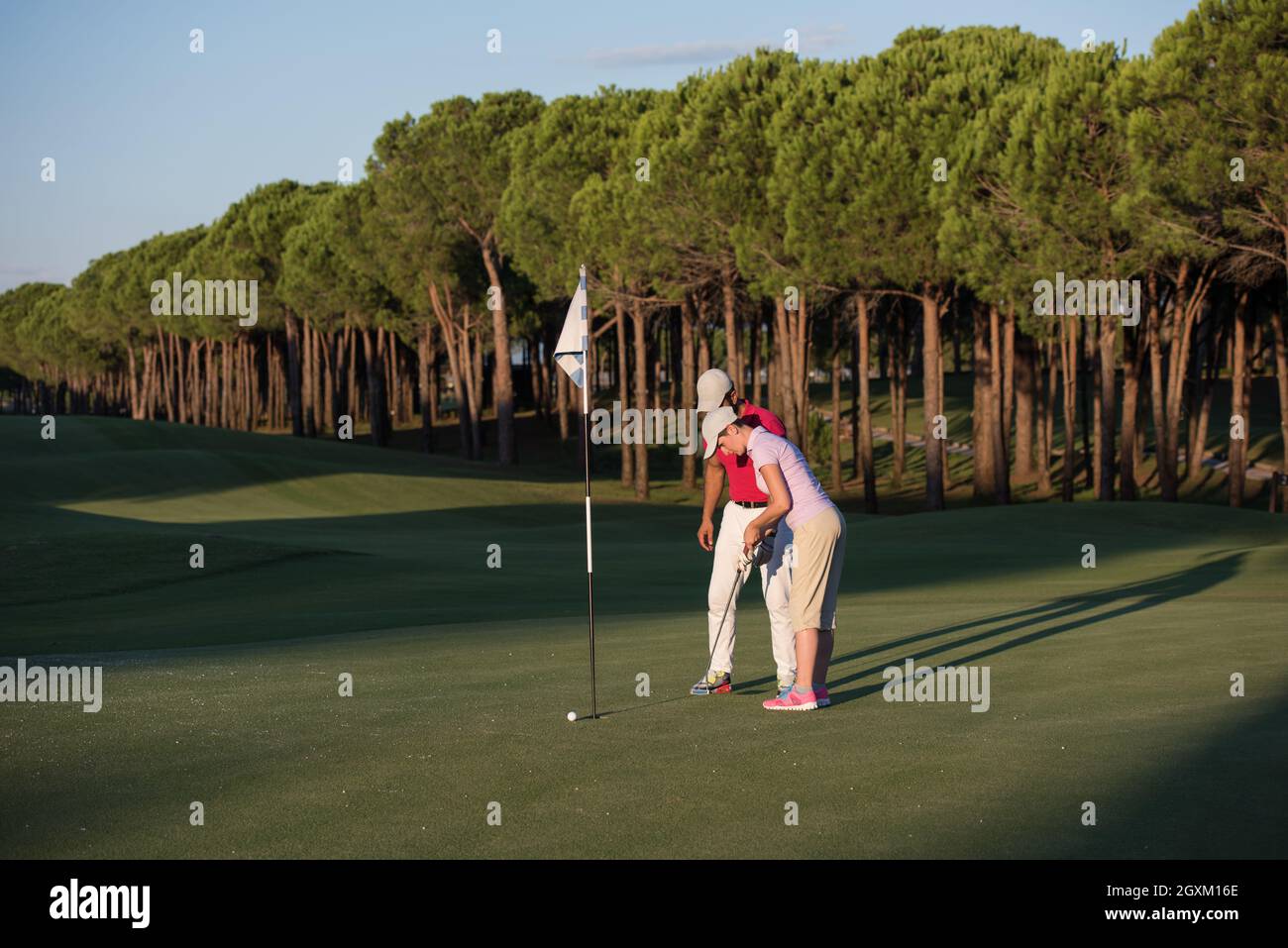 male golf instructor teaching female golf player, personal trainer ...