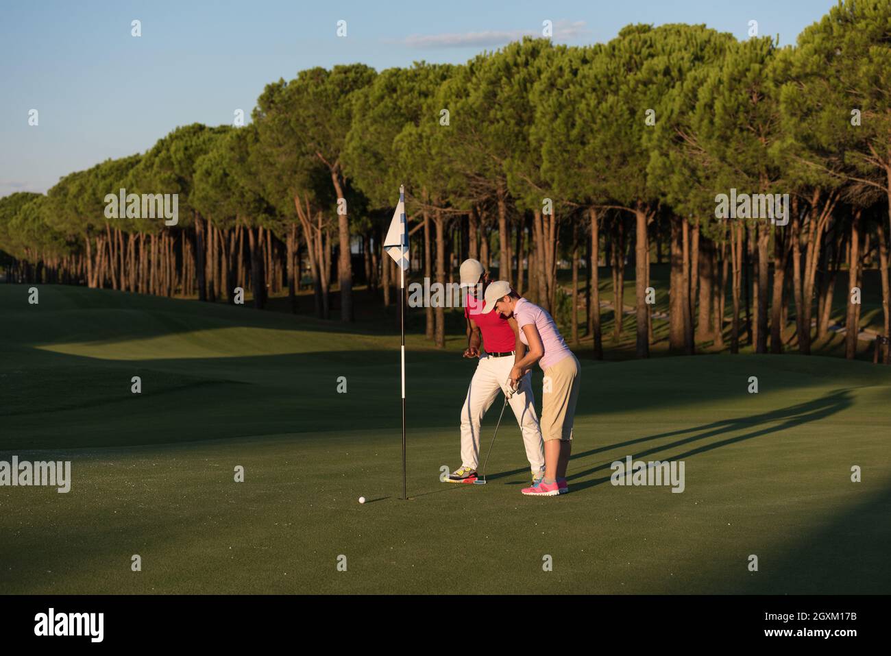 male golf instructor teaching female golf player, personal trainer ...