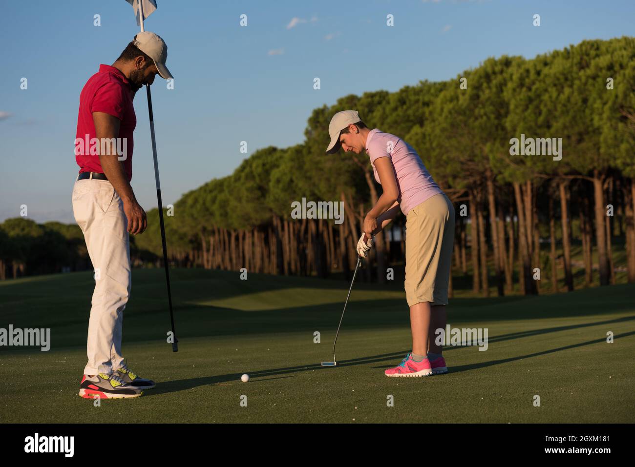 male golf instructor teaching female golf player, personal trainer ...