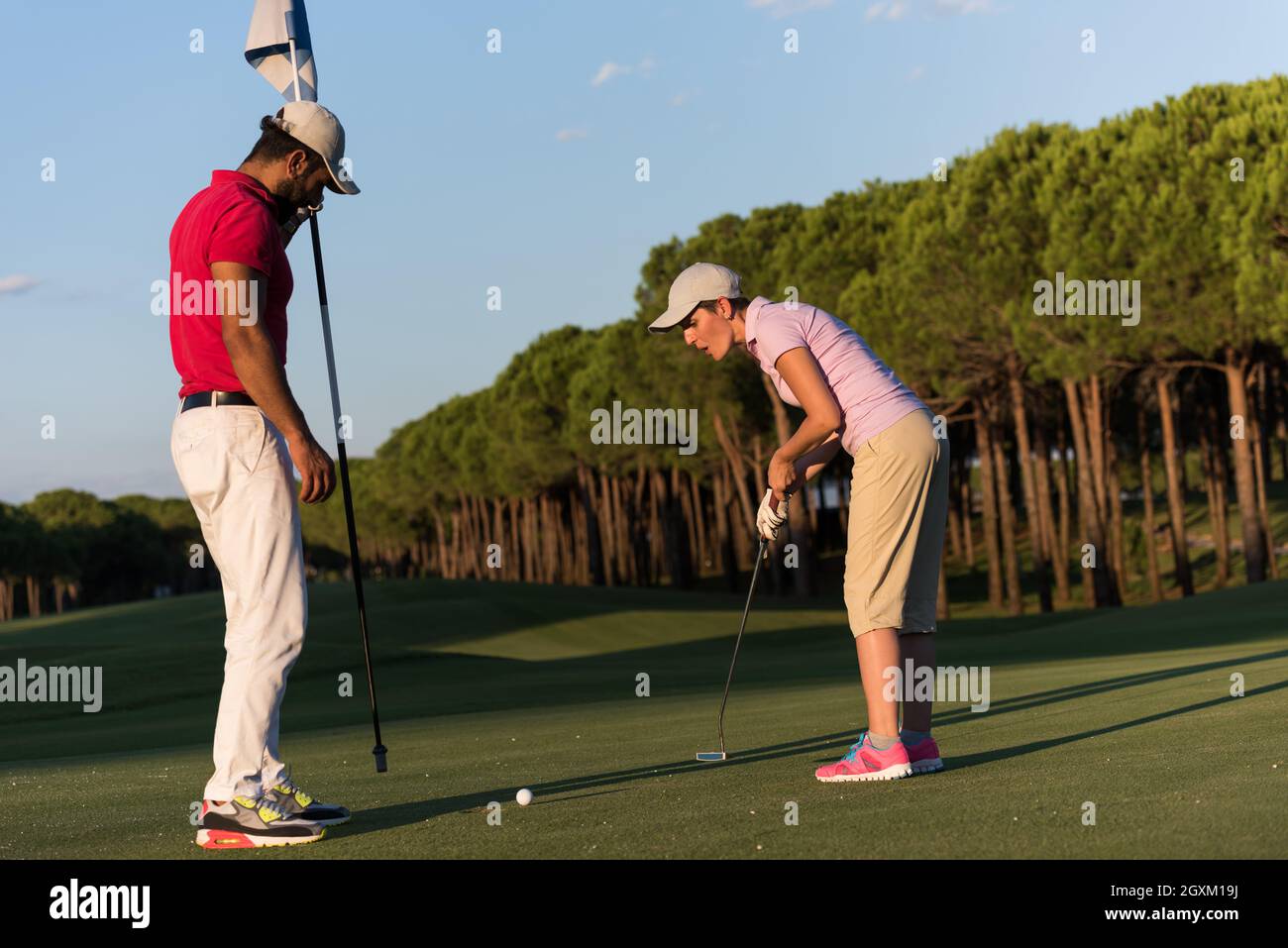 male golf instructor teaching female golf player, personal trainer ...
