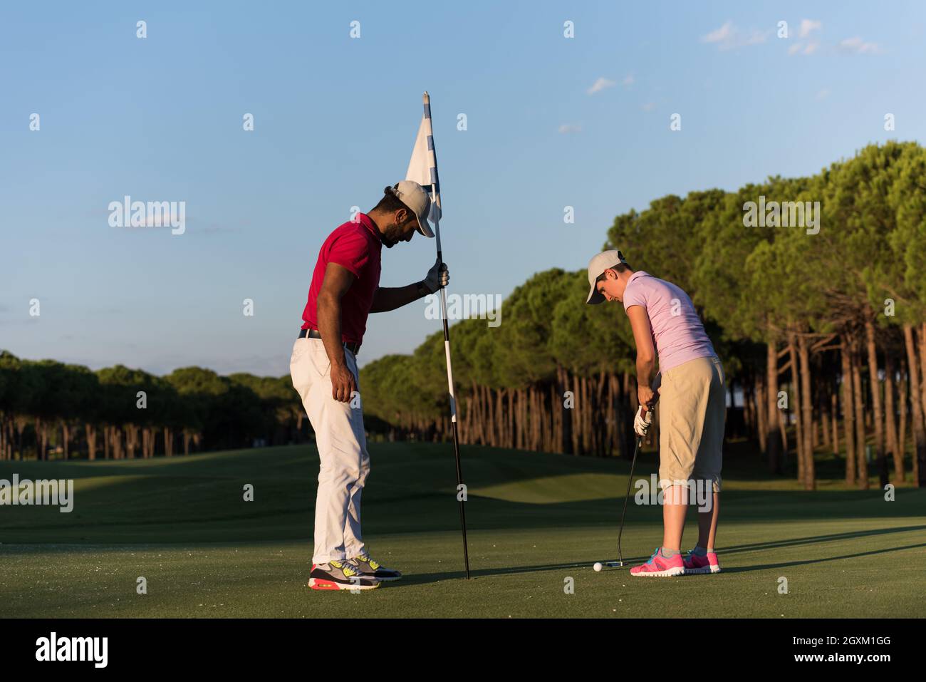 male golf instructor teaching female golf player, personal trainer ...