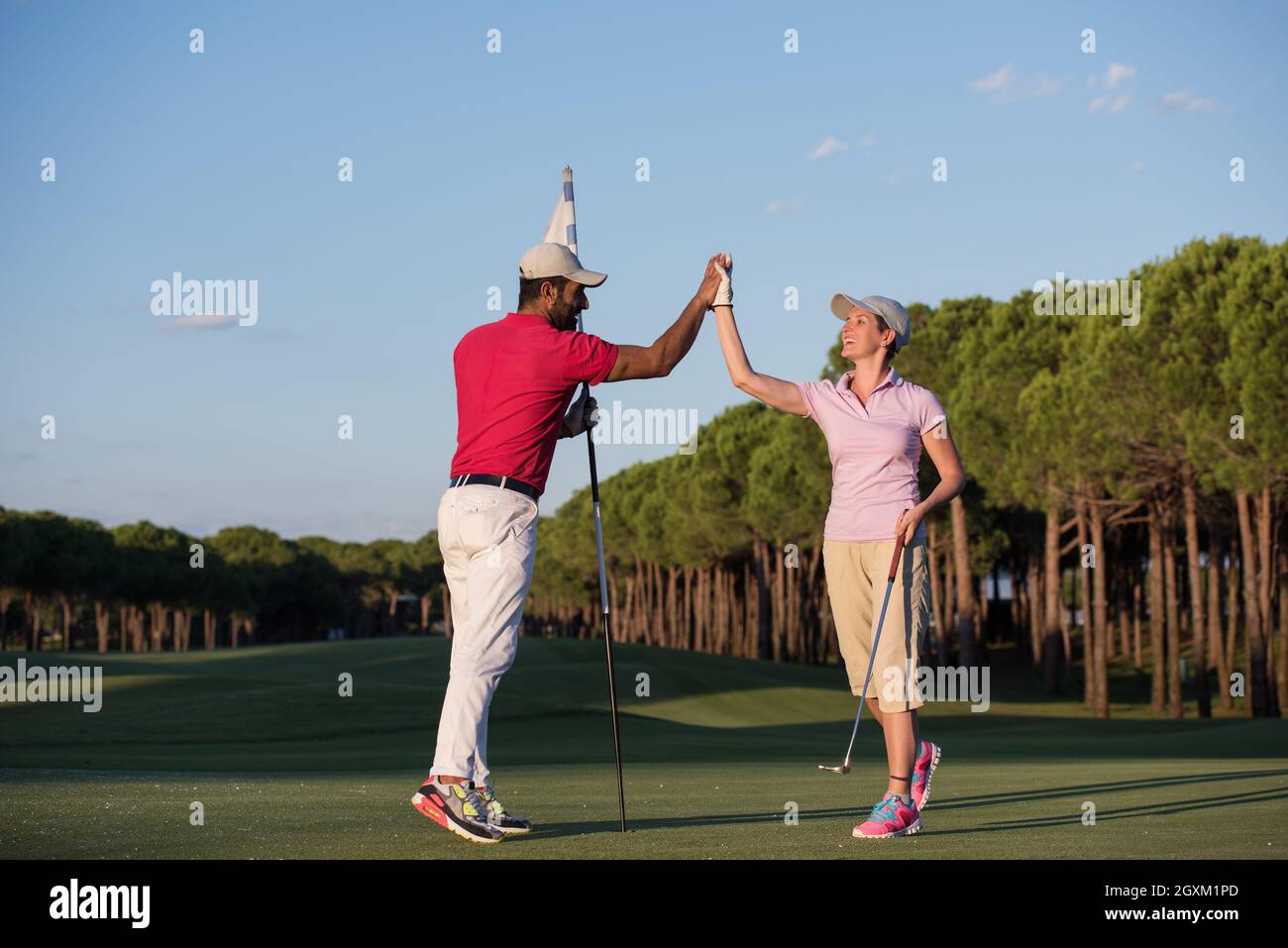 male golf instructor teaching female golf player, personal trainer ...