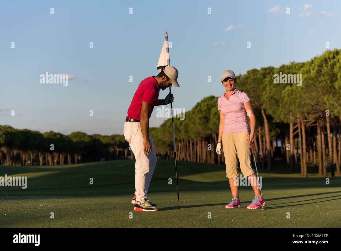 male golf instructor teaching female golf player, personal trainer ...