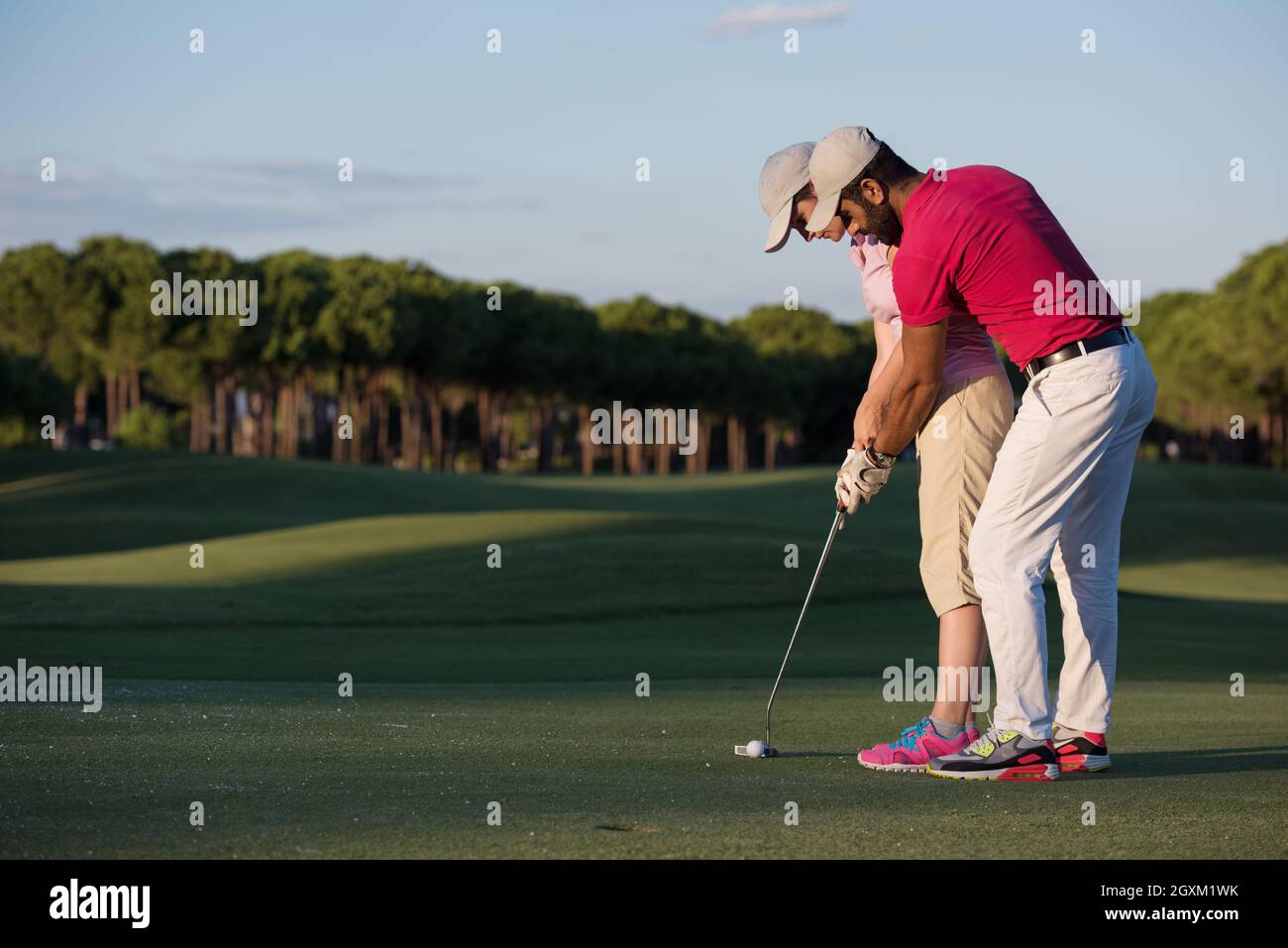 male golf instructor teaching female golf player, personal trainer ...