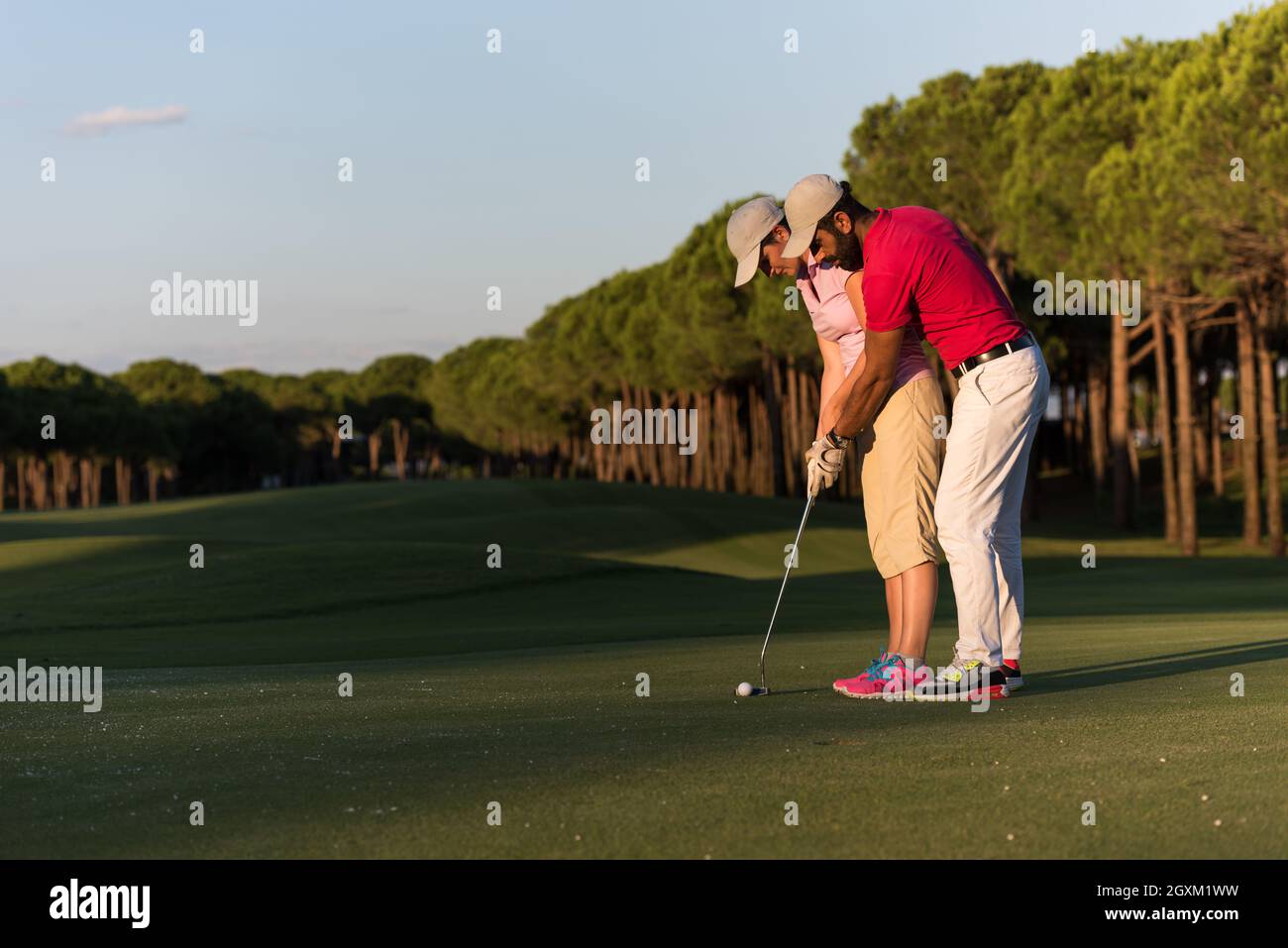 male golf instructor teaching female golf player, personal trainer ...