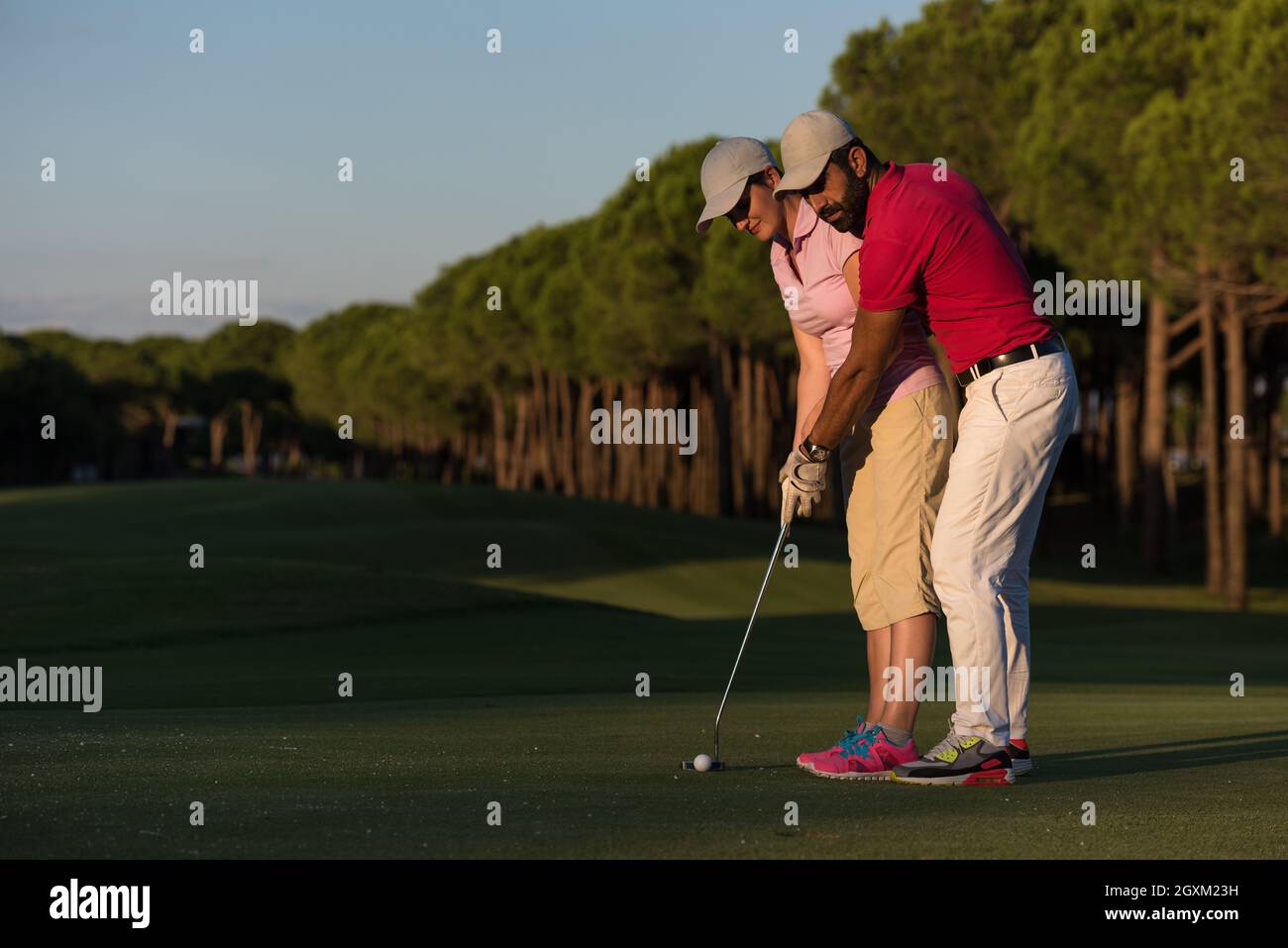 male golf instructor teaching female golf player, personal trainer ...