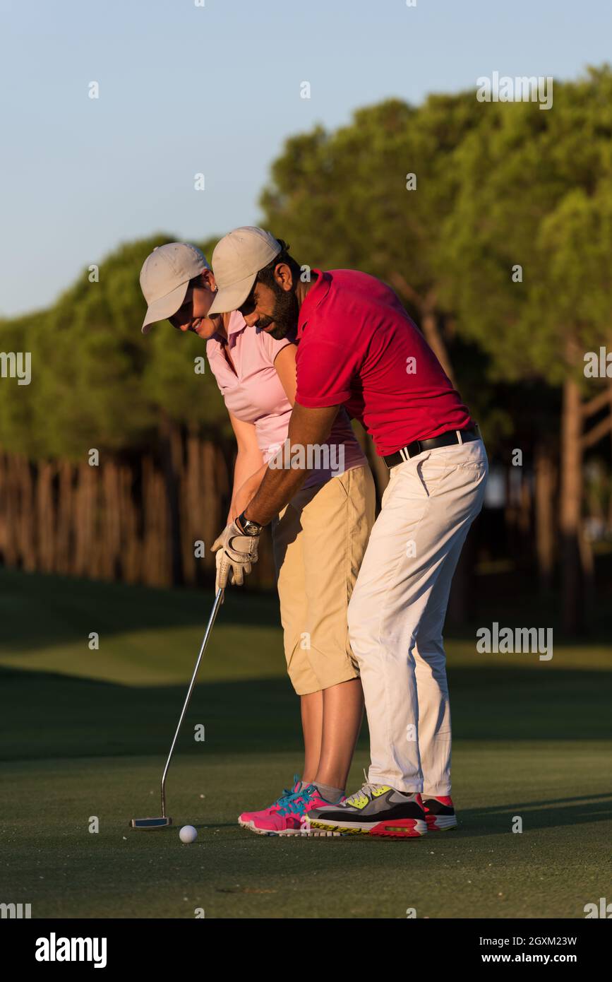 male golf instructor teaching female golf player, personal trainer ...