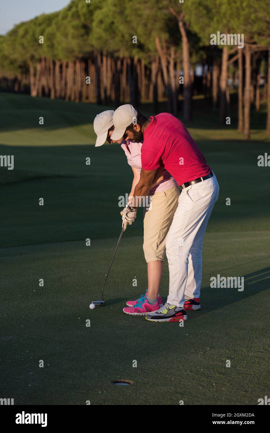 male golf instructor teaching female golf player, personal trainer ...