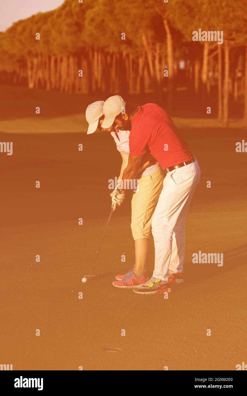 male golf instructor teaching female golf player, personal trainer ...