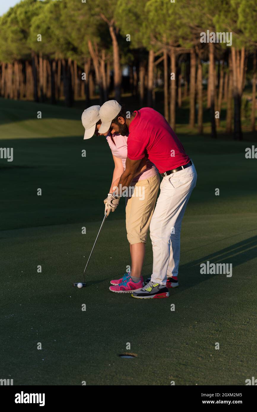 male golf instructor teaching female golf player, personal trainer ...