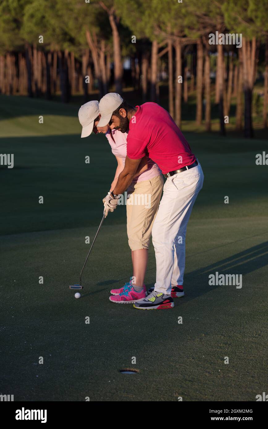 male golf instructor teaching female golf player, personal trainer ...