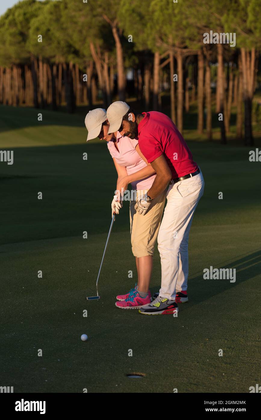 male golf instructor teaching female golf player, personal trainer ...