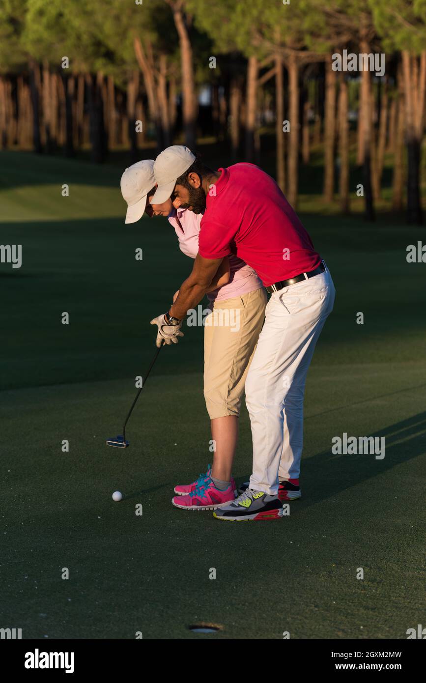 male golf instructor teaching female golf player, personal trainer ...
