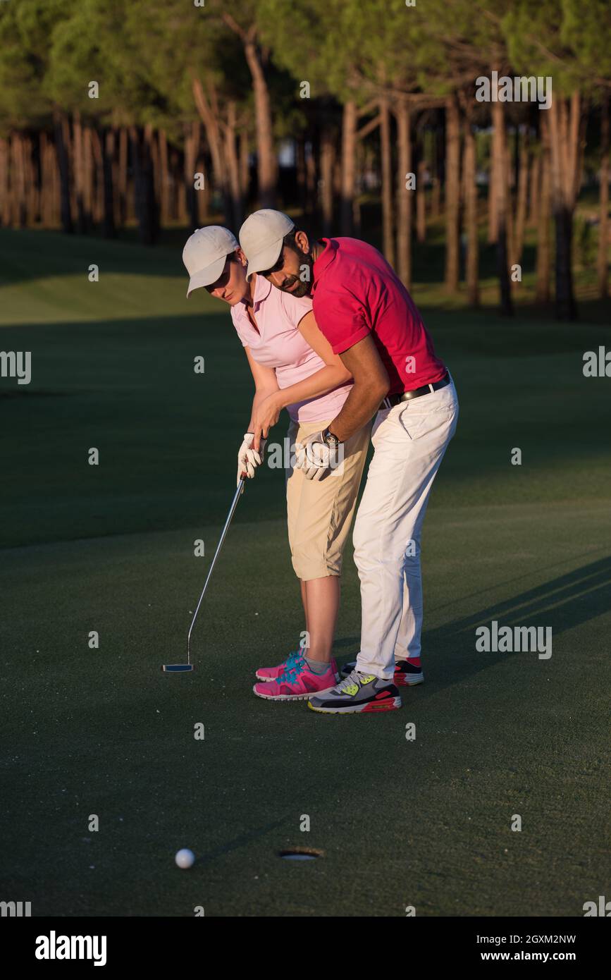 male golf instructor teaching female golf player, personal trainer ...