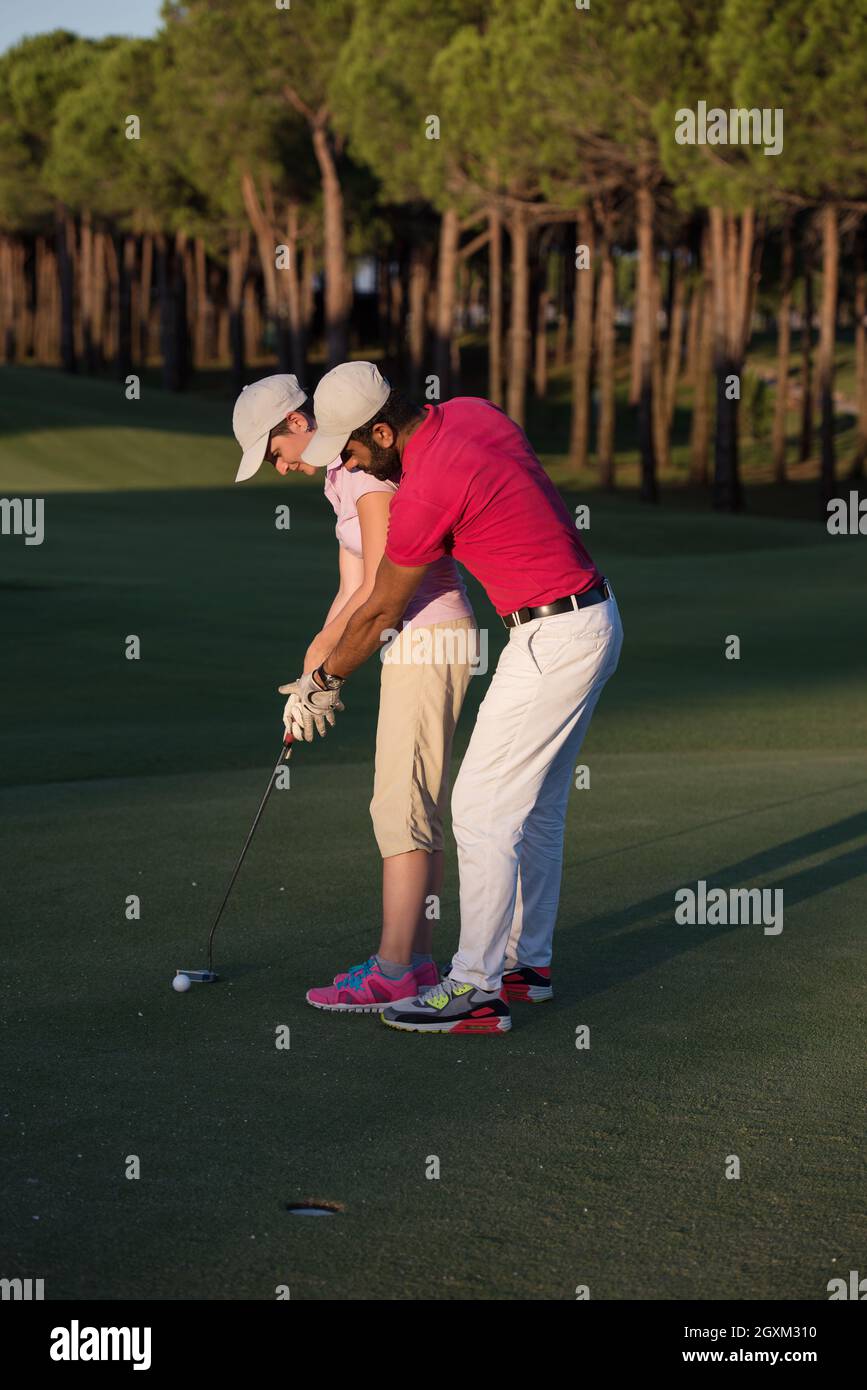 male golf instructor teaching female golf player, personal trainer ...