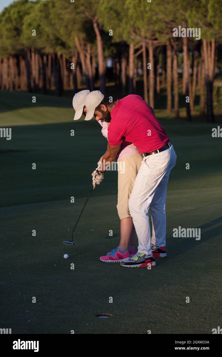 male golf instructor teaching female golf player, personal trainer ...