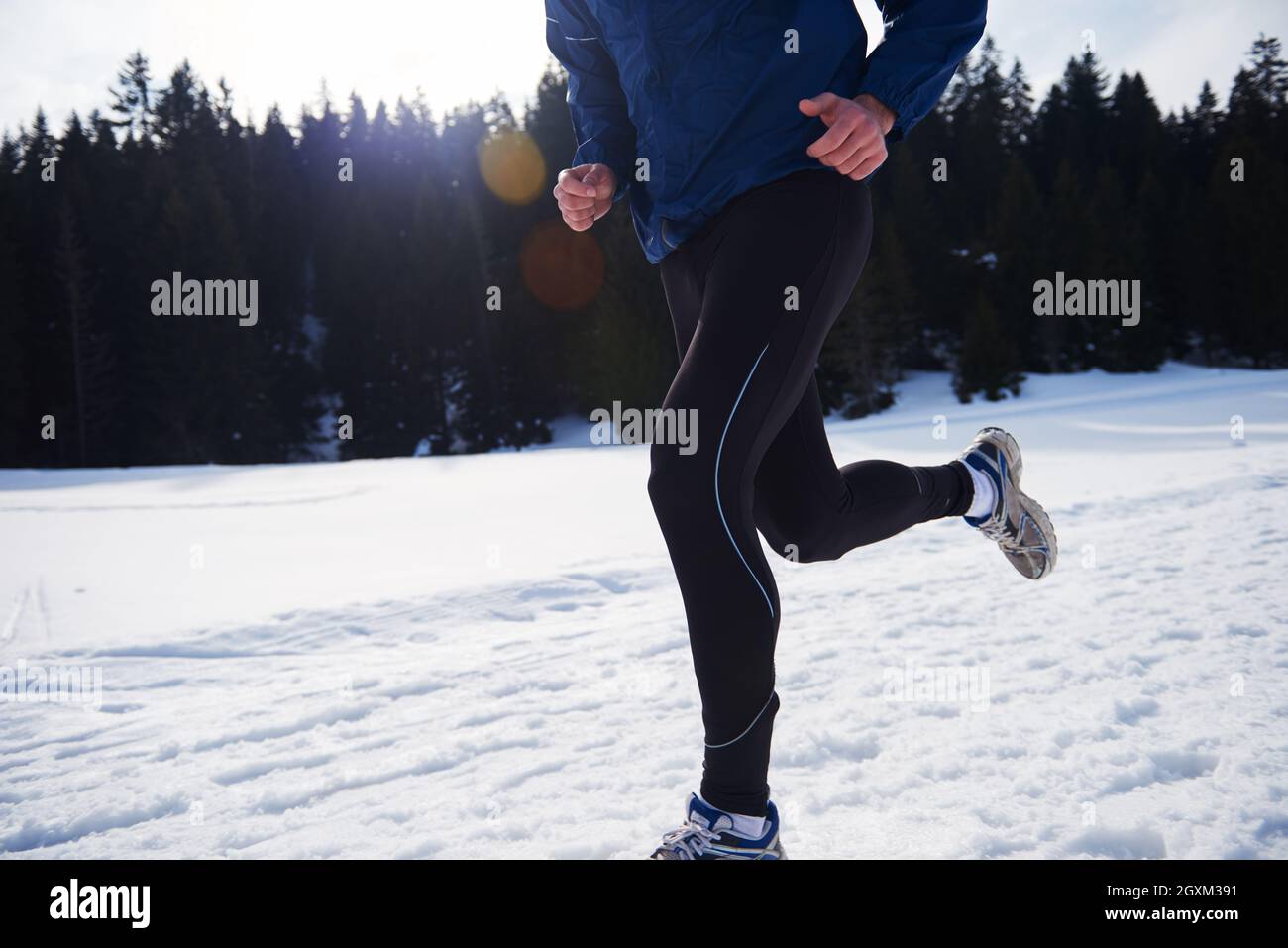 young man jogging on snow in forest, bautiful sunny winter day ...