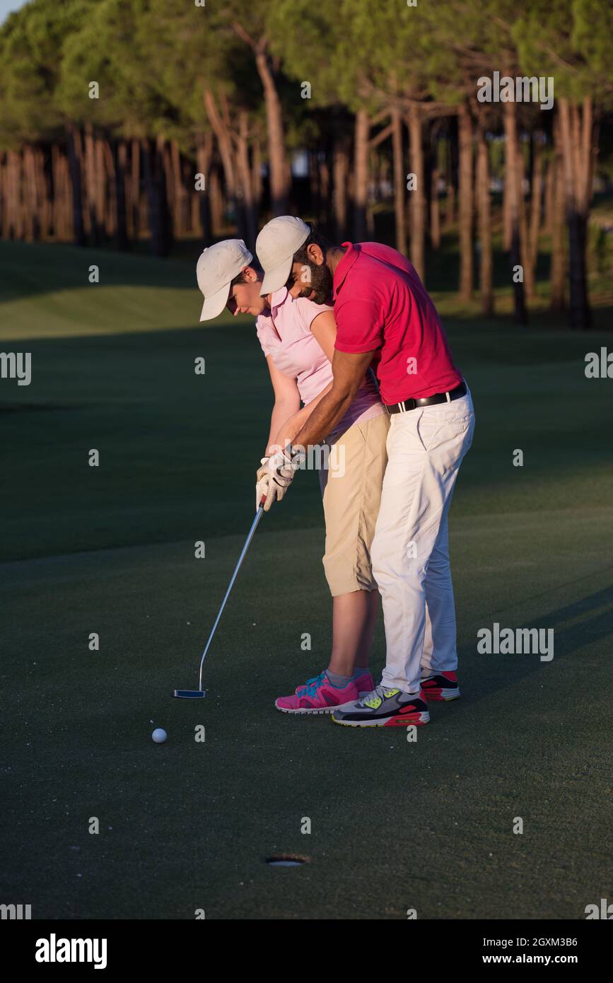 male golf instructor teaching female golf player, personal trainer ...