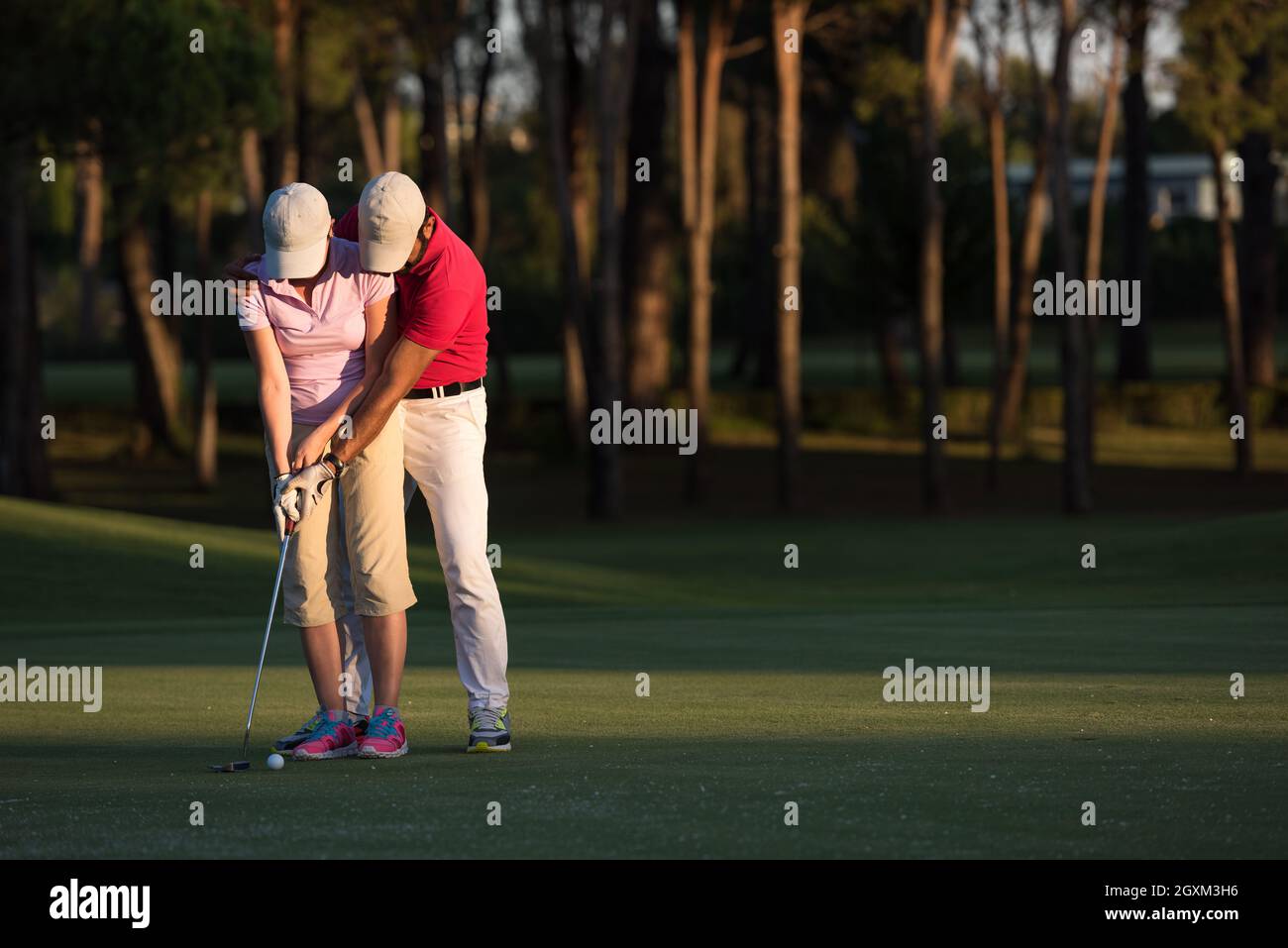 male golf instructor teaching female golf player, personal trainer ...
