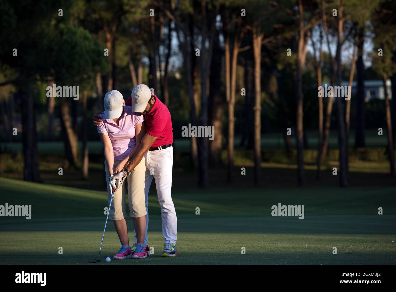 male golf instructor teaching female golf player, personal trainer ...