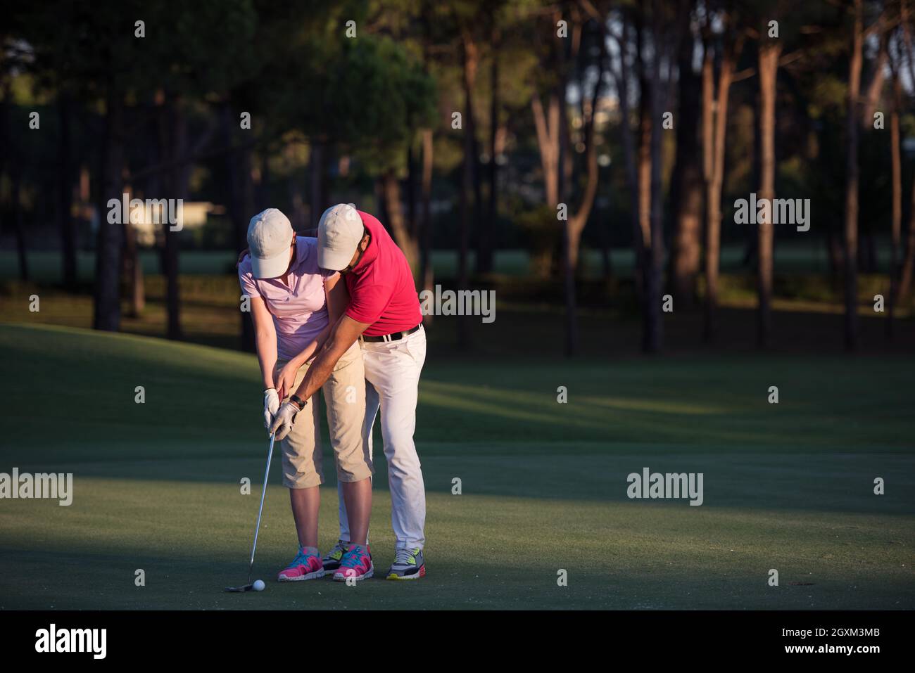 male golf instructor teaching female golf player, personal trainer ...