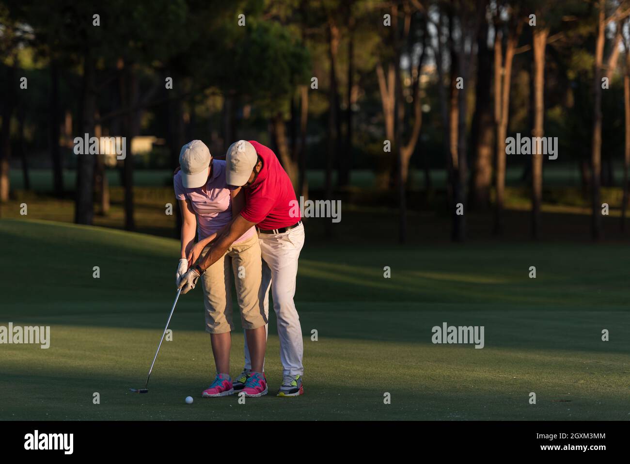 male golf instructor teaching female golf player, personal trainer ...