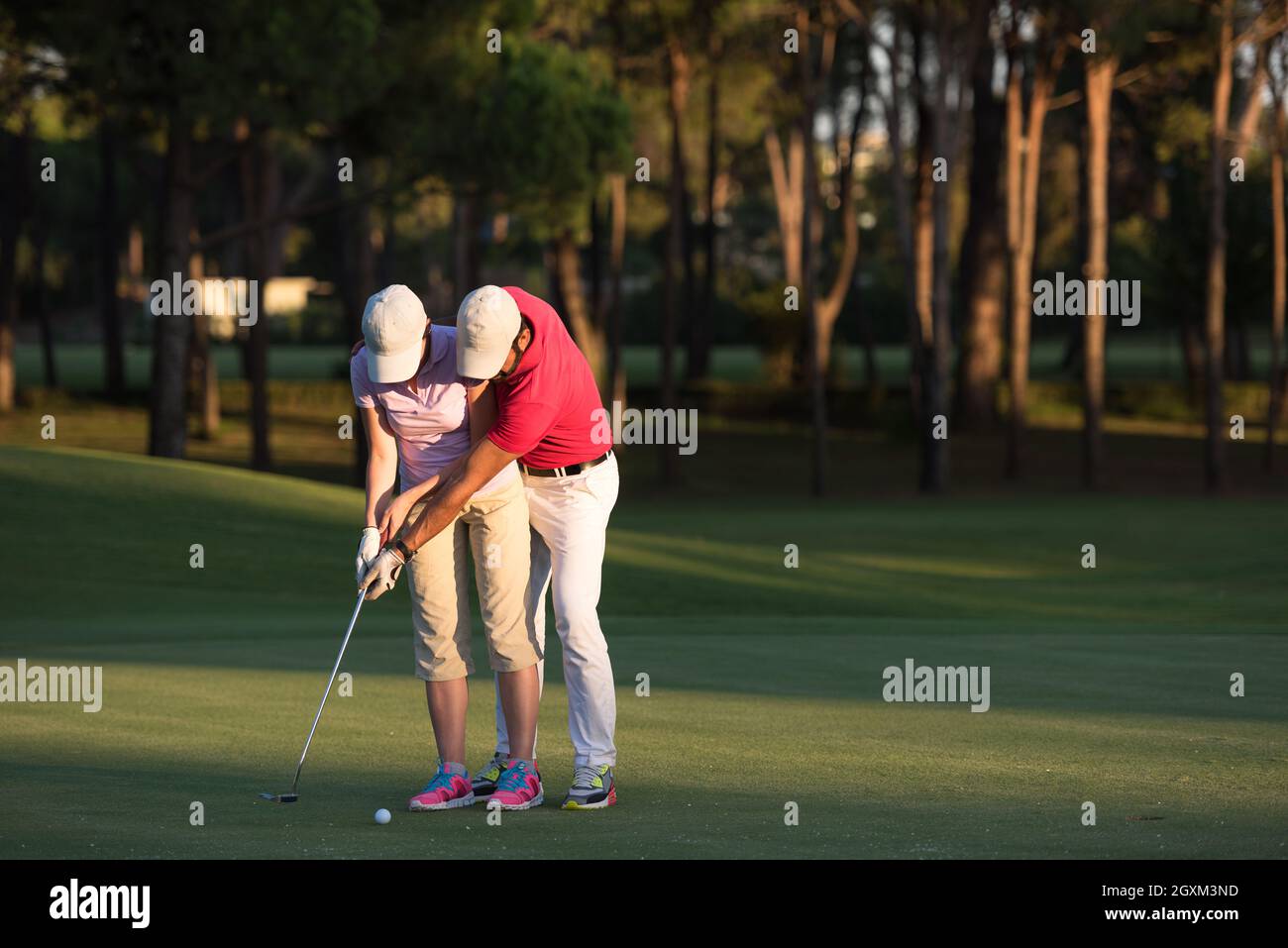 male golf instructor teaching female golf player, personal trainer ...