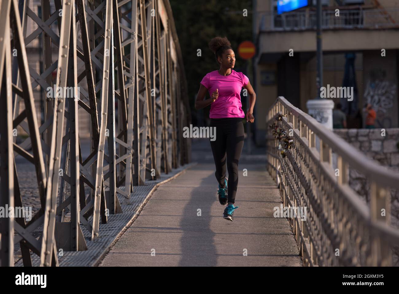 Young sporty african american woman running on sidewalk across the ...