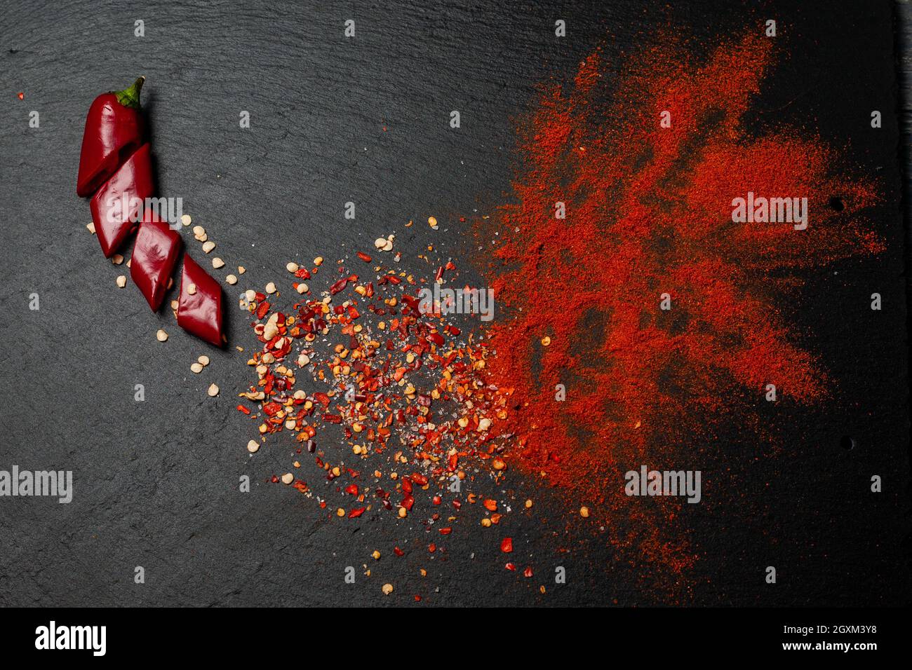 Red chili pepper explosion isolated on black slate board. Copyspace ...
