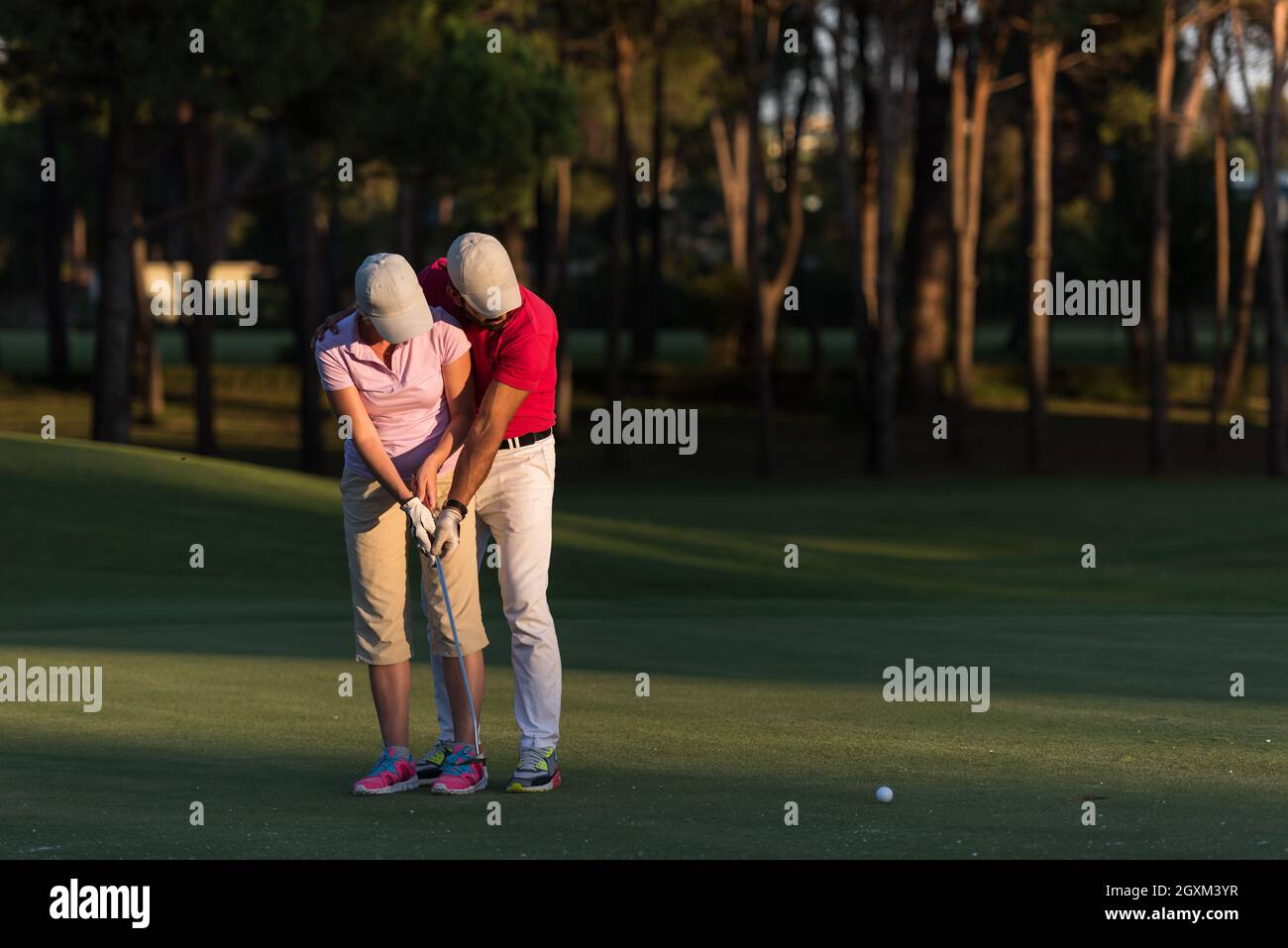 male golf instructor teaching female golf player, personal trainer ...