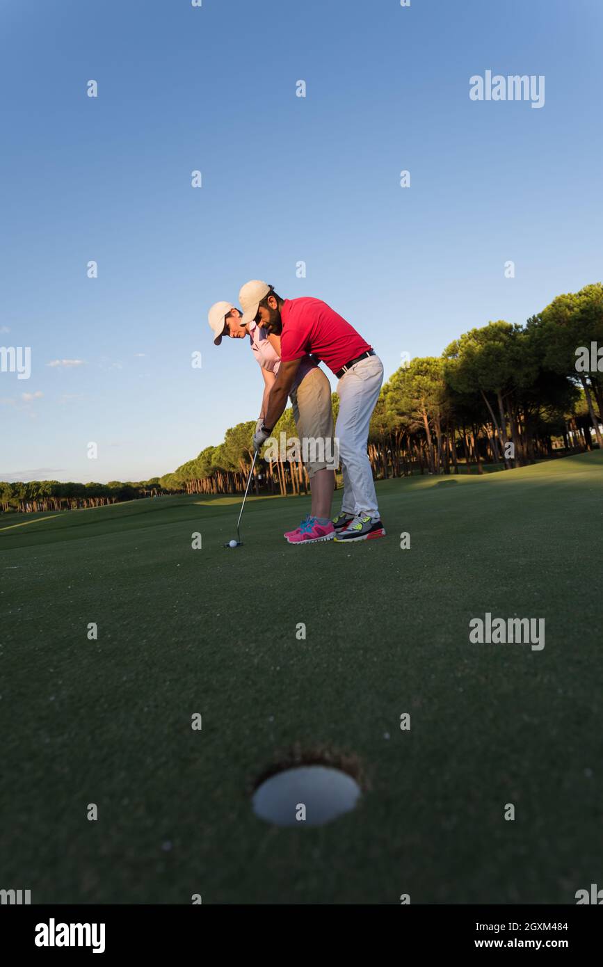 male golf instructor teaching female golf player, personal trainer ...