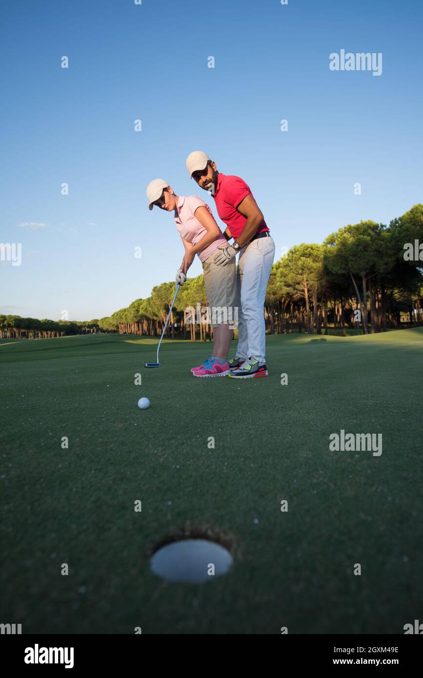 male golf instructor teaching female golf player, personal trainer ...