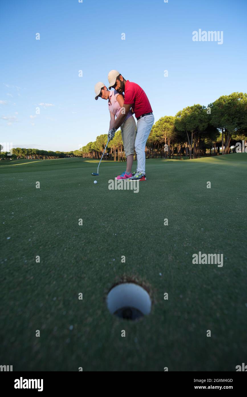 male golf instructor teaching female golf player, personal trainer ...