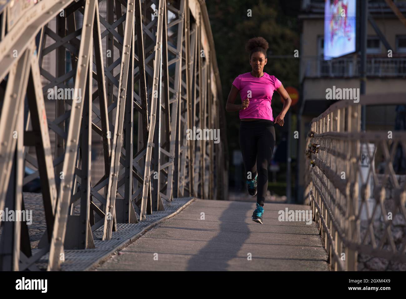 Young sporty african american woman running on sidewalk across the ...