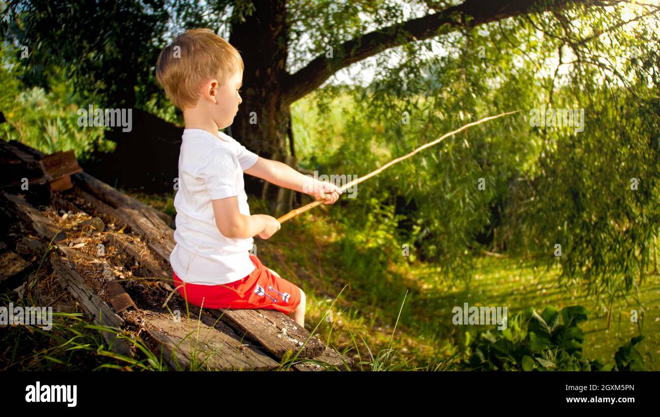 Cute little child fishing at pond on the sunset Stock Photo - Alamy