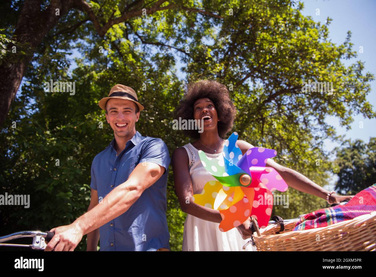 a young man and a beautiful African American girl enjoying a bike ride in nature on a sunny ...