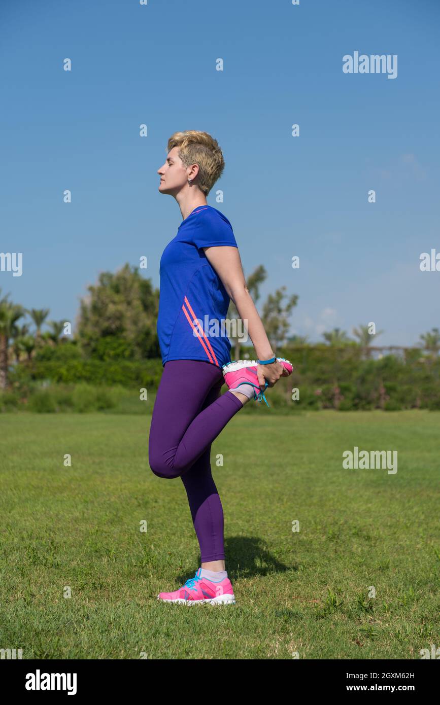 healthy female runner warming up and stretching before morning training ...