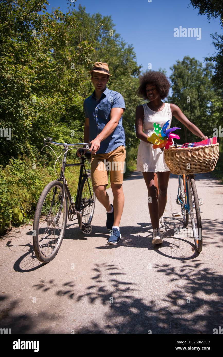 a young man and a beautiful African American girl enjoying a bike ride in nature on a sunny ...