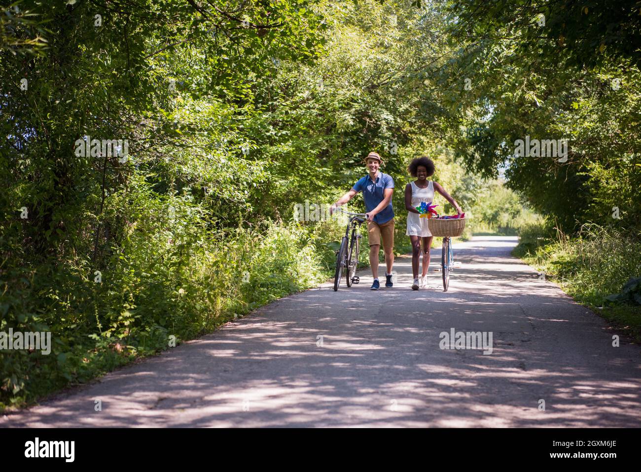 a young man and a beautiful African American girl enjoying a bike ride in nature on a sunny ...