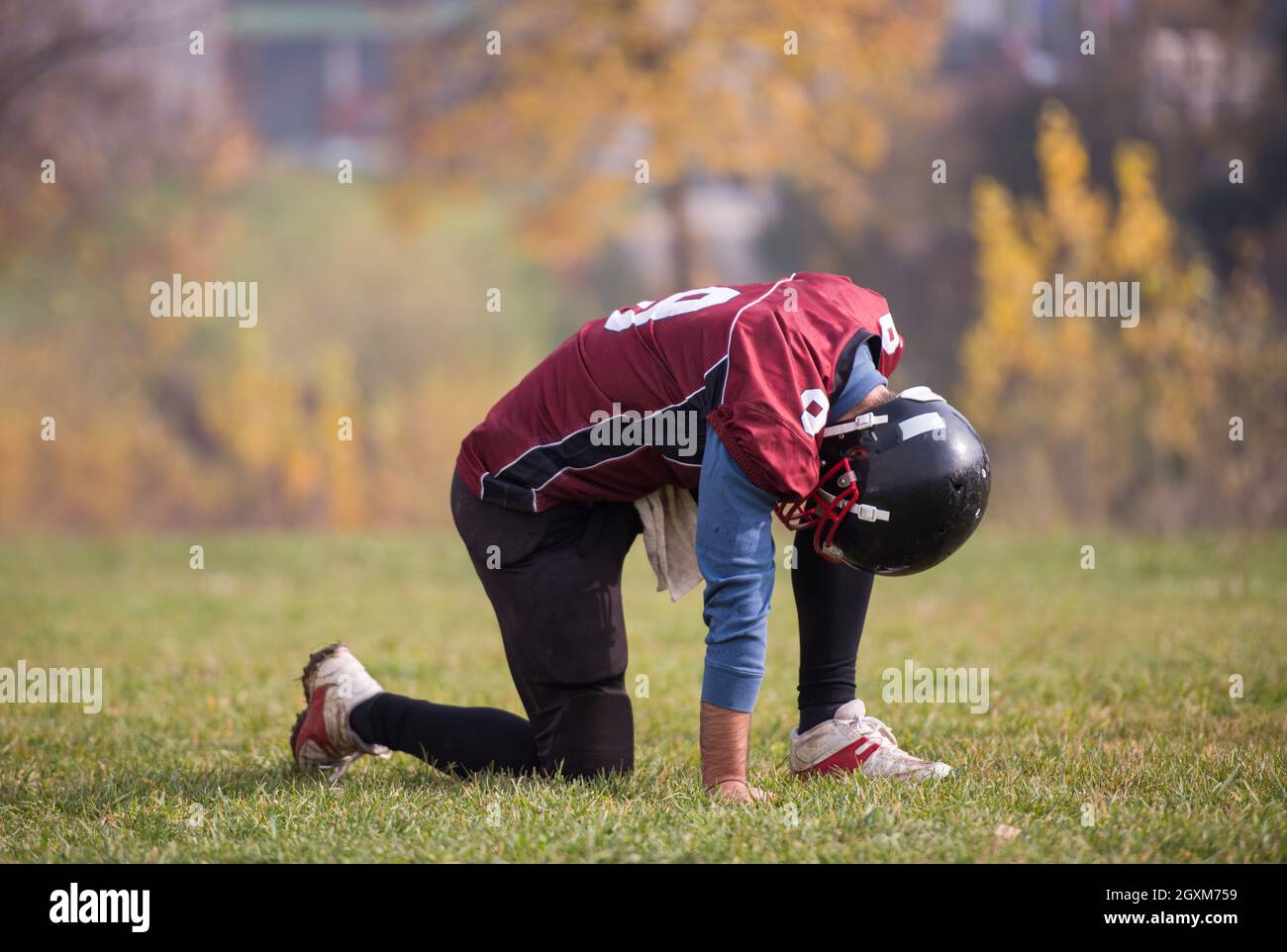 A tired american football player resting after hard training at field ...