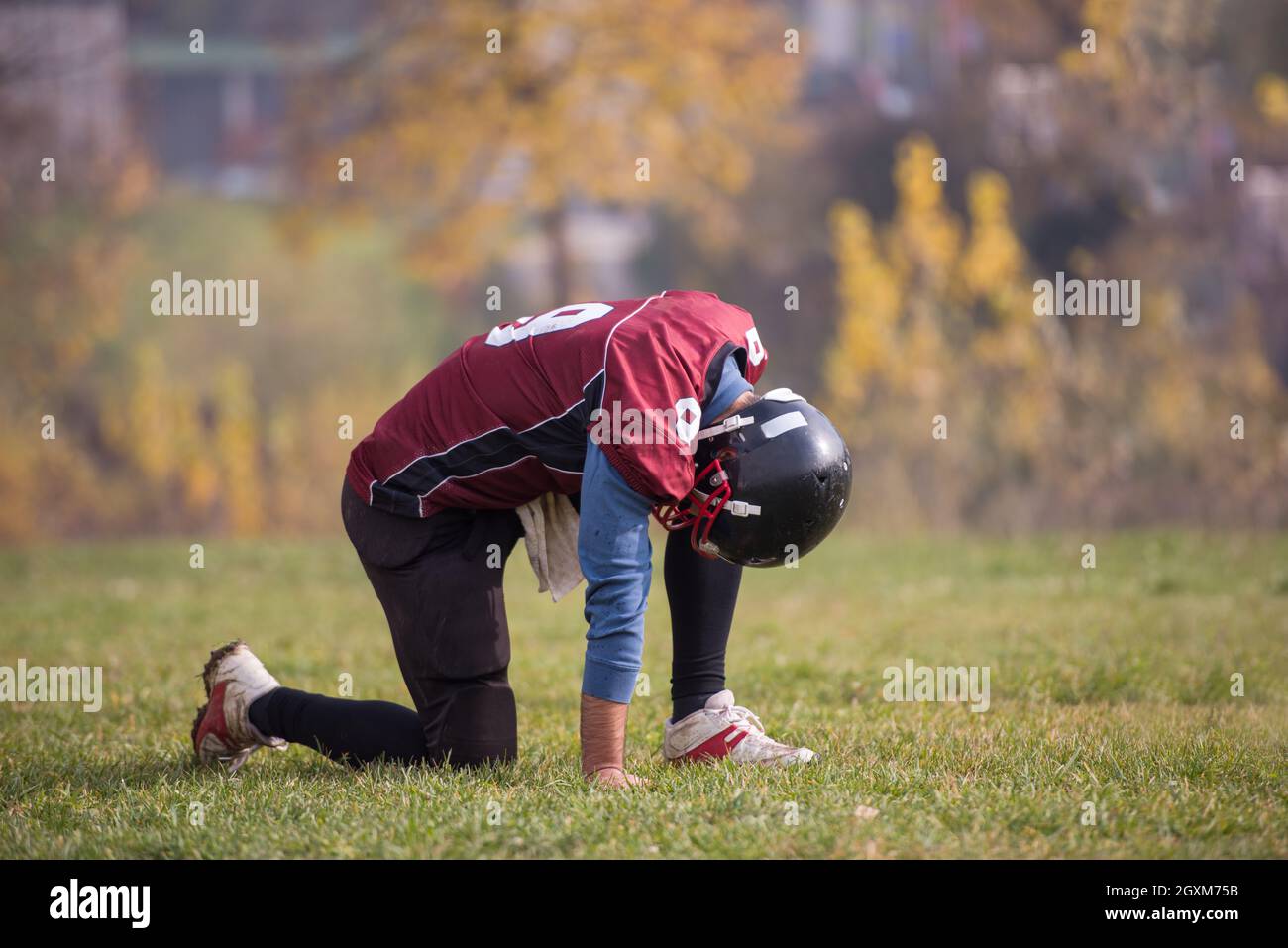 A tired american football player resting after hard training at field ...