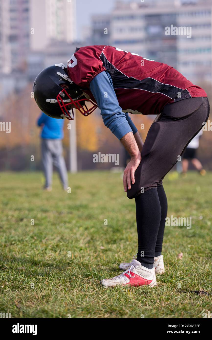 A tired american football player resting after hard training at field ...
